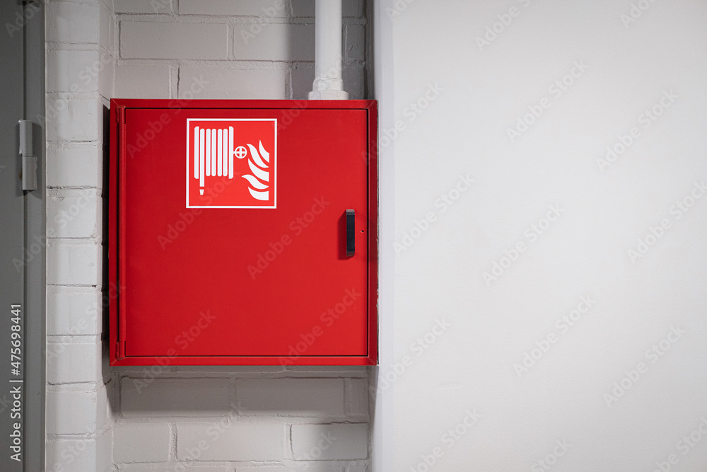 Fire cabinet with extinguisher and hydrant hose on white wall ...