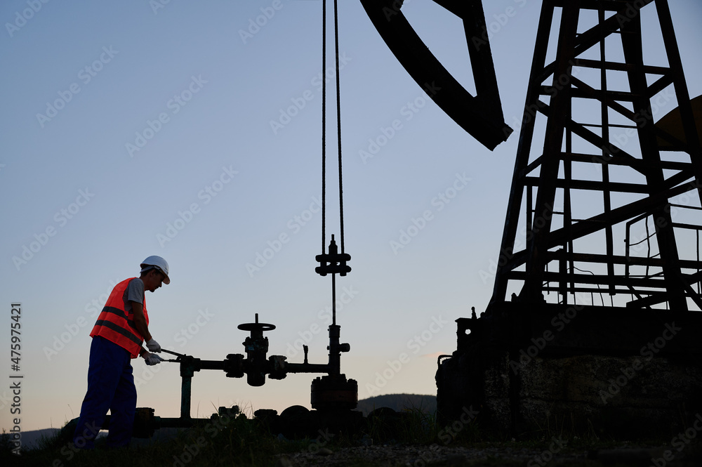 Стоковое фото «Petroleum operator in work vest using oil pump rocker ...