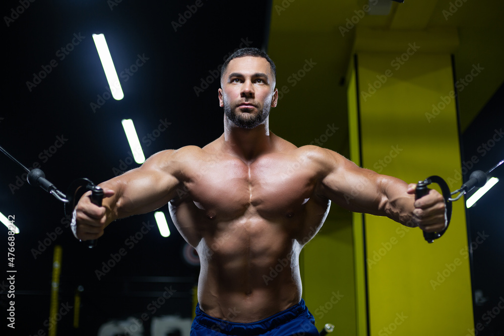 Front view portrait of a bodybuilder working on his chest muscles with ...