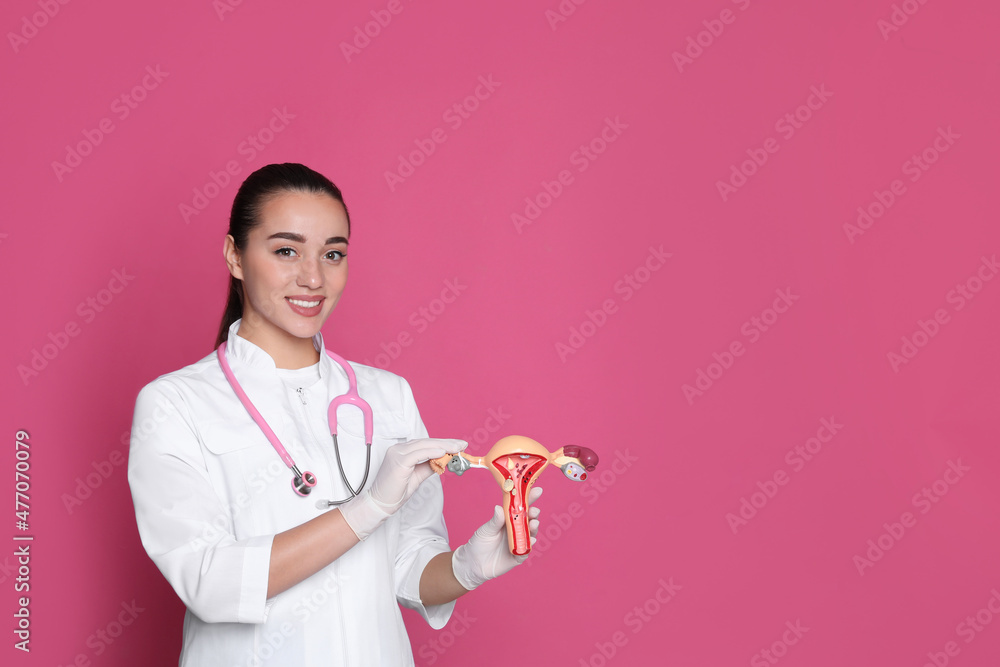Doctor demonstrating model of female reproductive system on pink ...