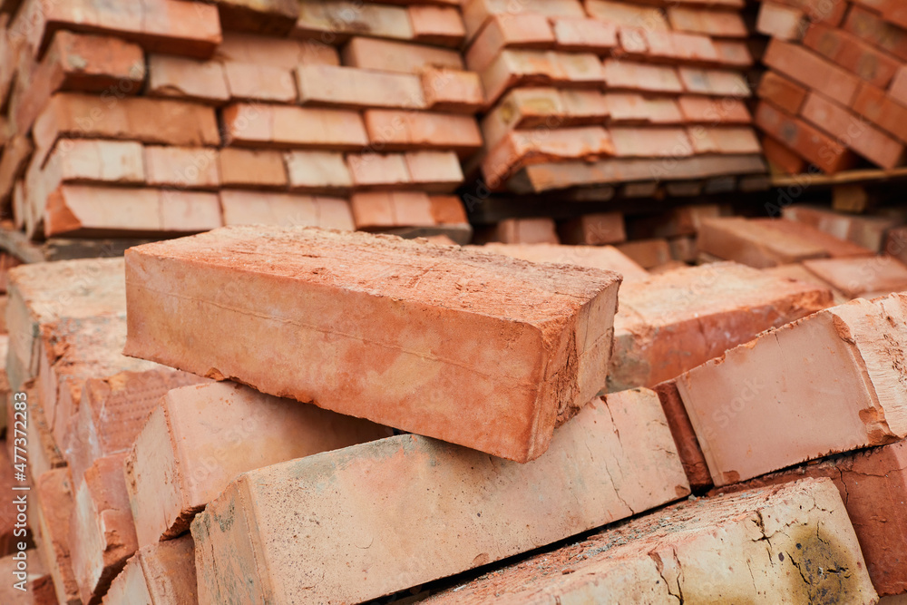 A stack of red clay bricks in rows close up. Lot of stacks of bricks on ...
