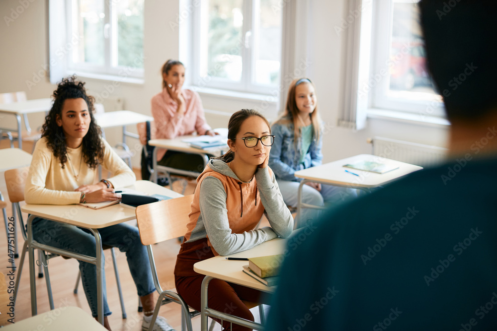 Teenage girl and her classmates paying attention during teacher's ...