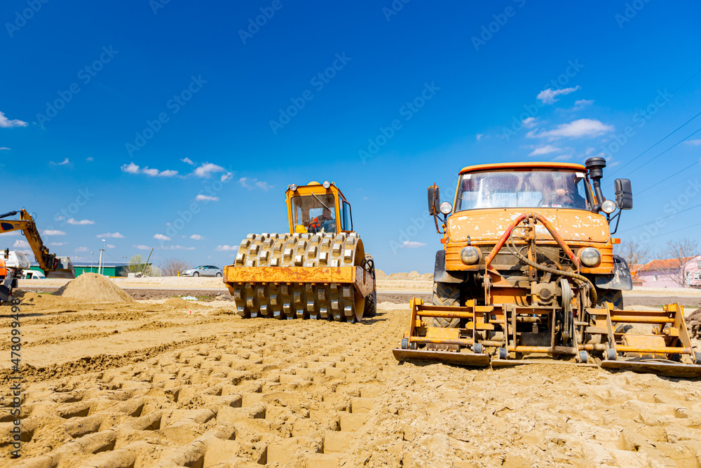 Road roller with spikes and truck plate compactor are working at ...