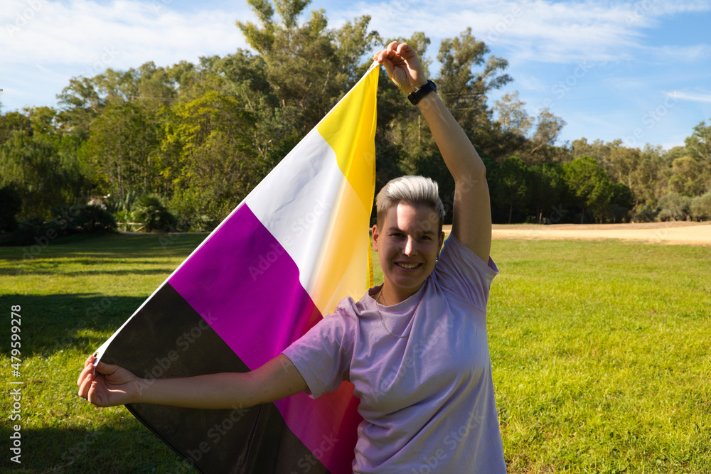 gender non-binary person is holding the flag of non-binary pride in his ...
