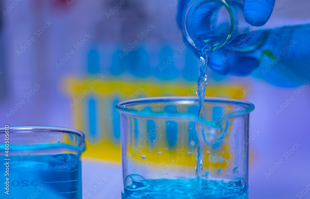 Closeup studio shot of blue solution reagent liquid sample pouring from ...