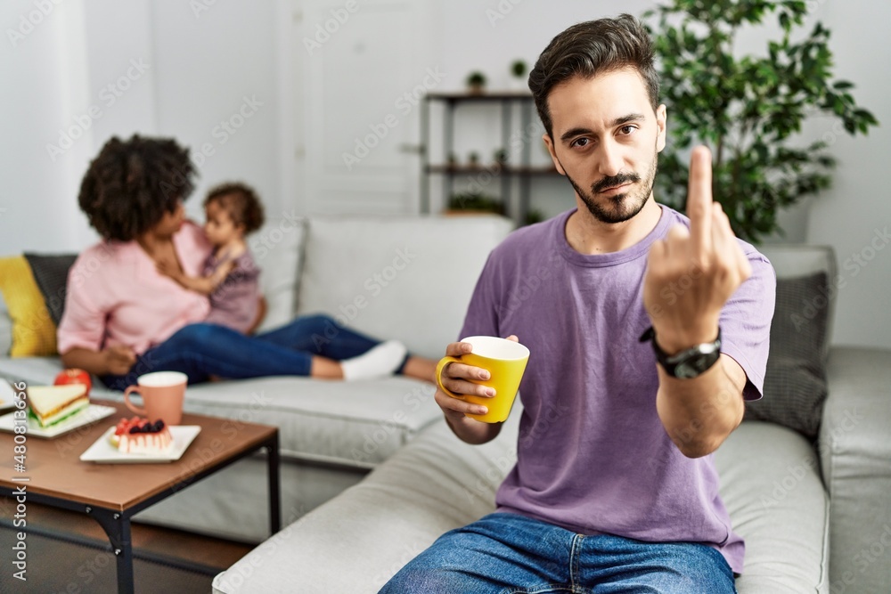 Hispanic father of interracial family drinking a cup coffee showing ...