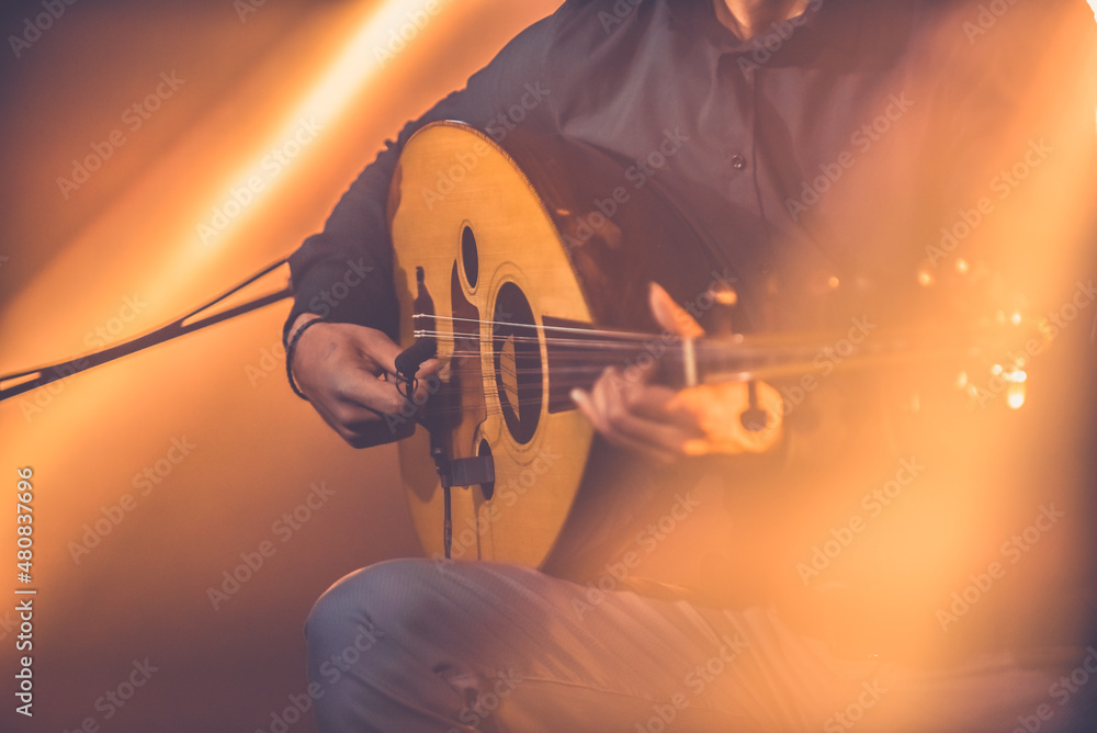 Toned image of musician playing traditional Turkish oud during concert ...