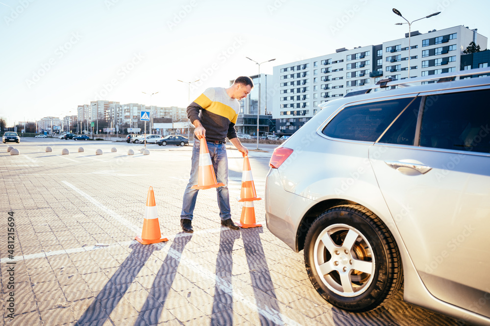 Male instructor teaching learner driver to park a car on the training ...