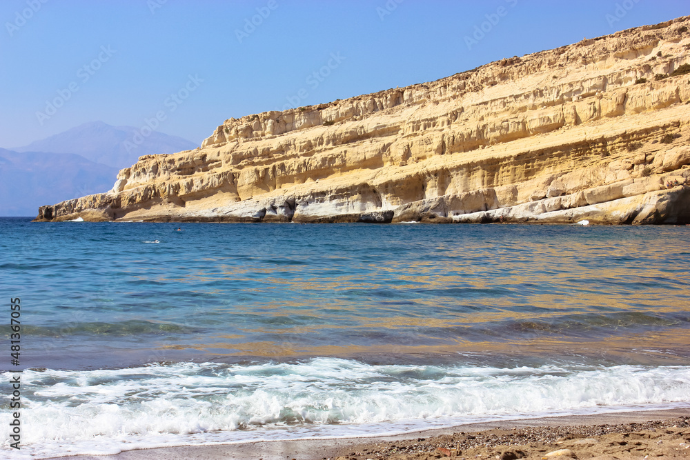 Sandy Matala beach with cliff, cliffs along a sea shore, caves against ...