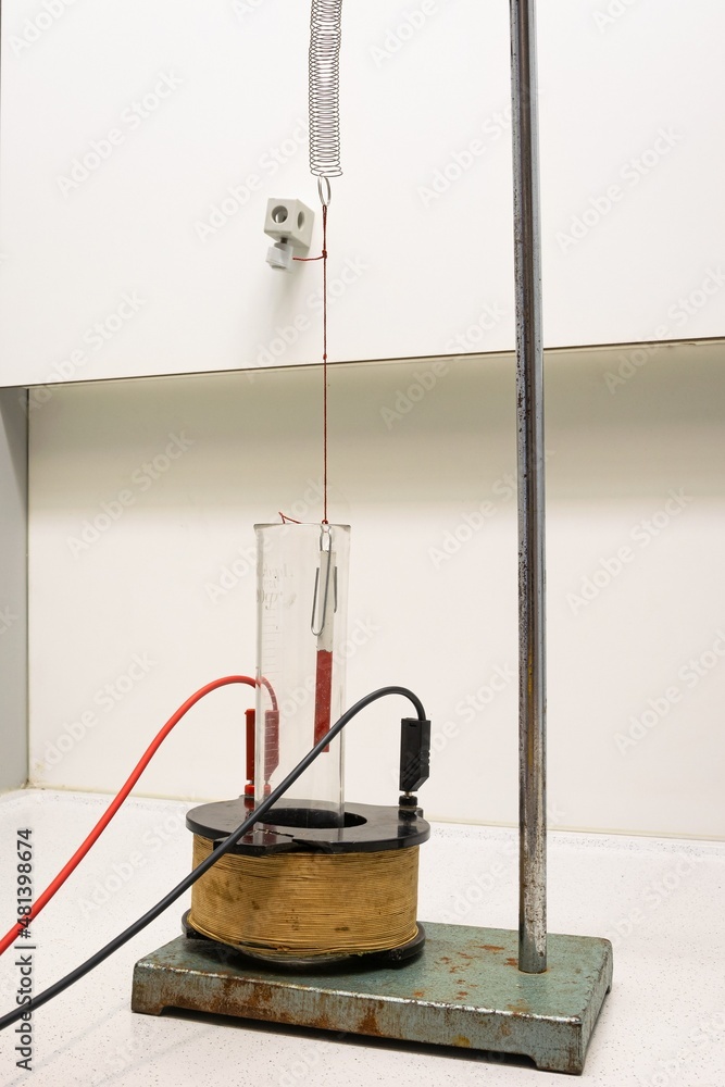 Stock-Foto „Magnet hanging from a spring vibrates through an ...
