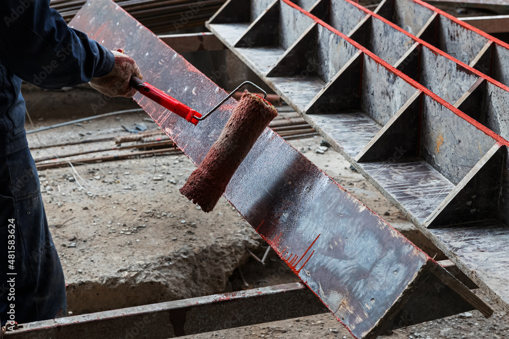 The worker covers the modular steel formwork with grease before lifting ...