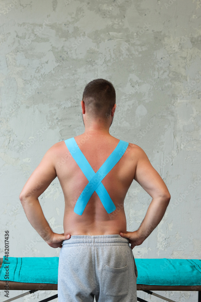 Muscular man with kinesiotaping on the back and shoulders ...