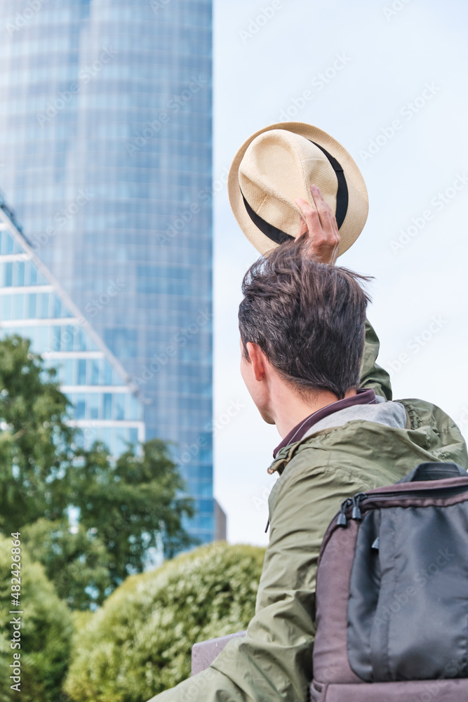 Man waving his raised hat against the backdrop of an office building ...