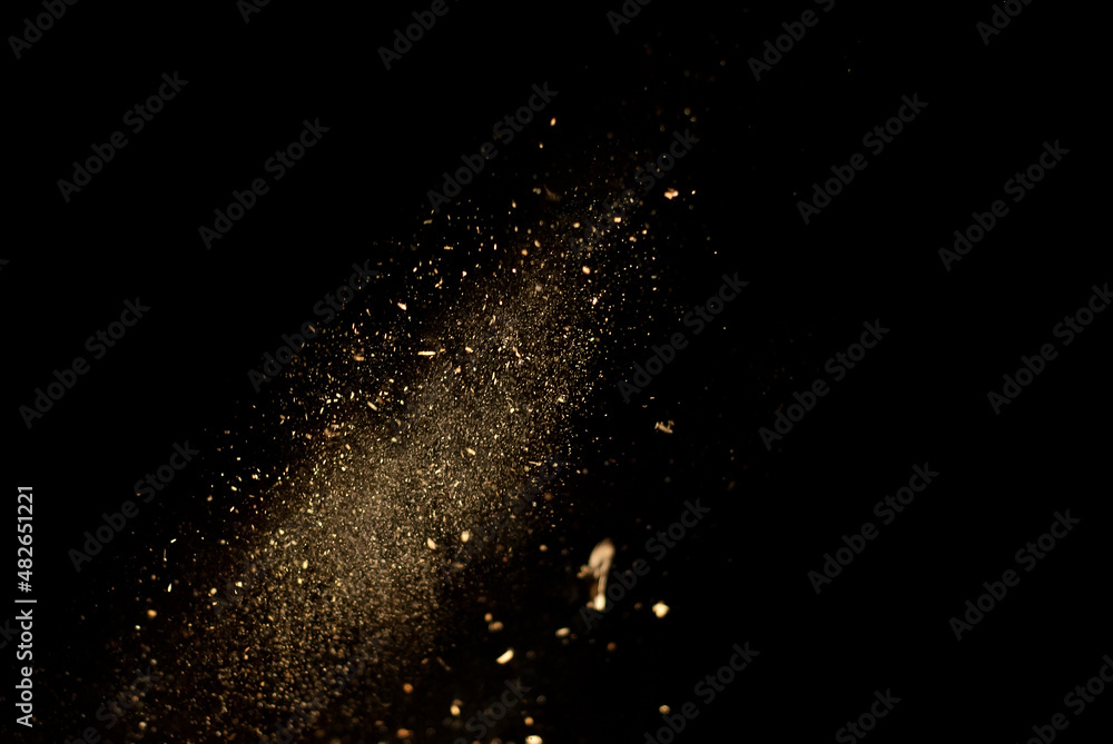 Dust and wood chips on a black background. Dirt particles fly in the ...