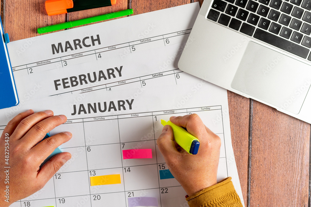 Top view of person using markers to highlight activities on calendar ...