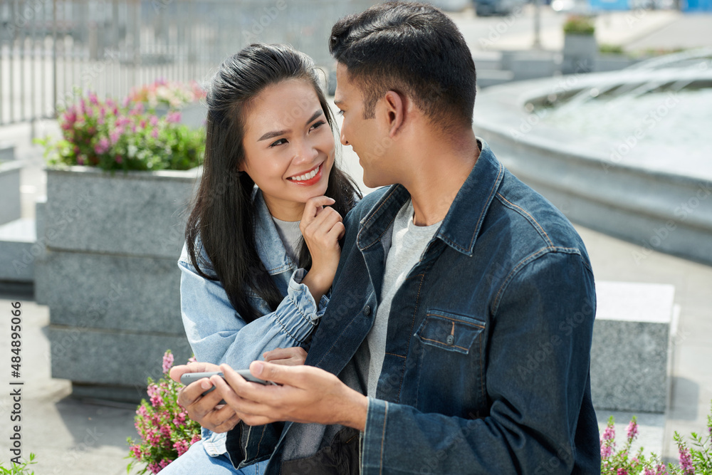 Smiling young woman in love looking at boyfriend who is explaining her ...