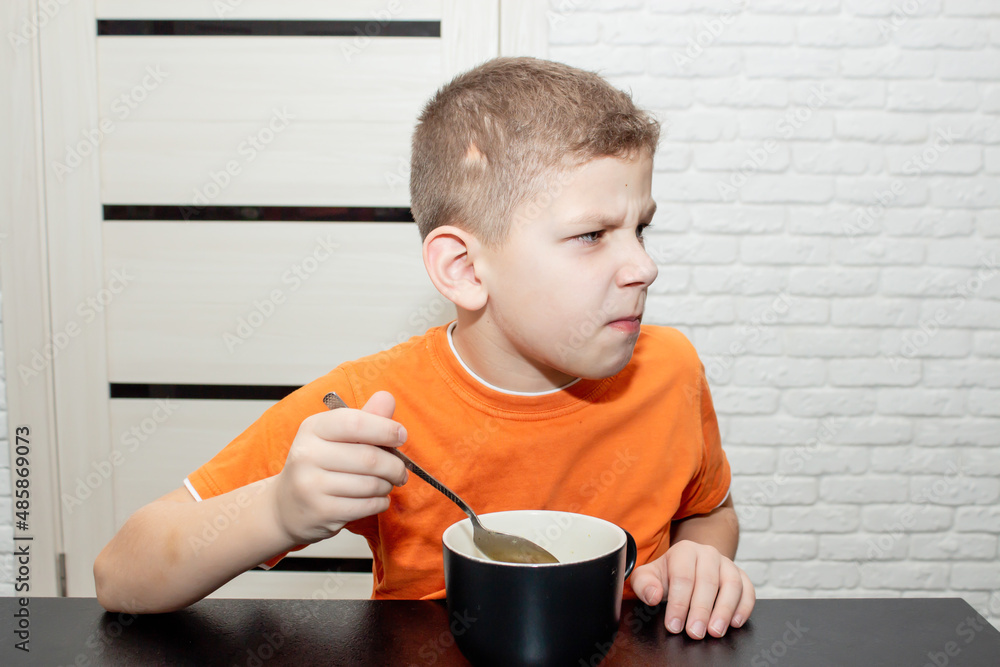Naughty boy eats at the table. The boy does not like the food, he gets ...