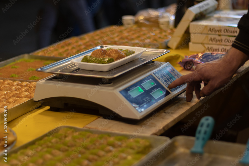 Old man hand weighing Turkish baklava with green pistachio on ...