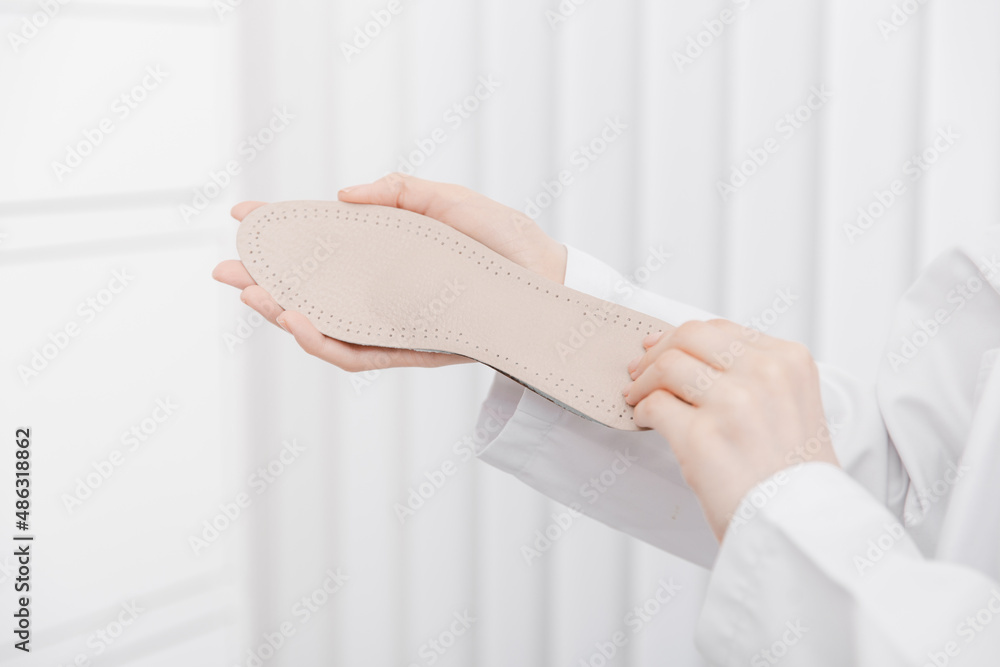 Doctor holding orthopedic insoles in his hands. Orthopedist tests the ...