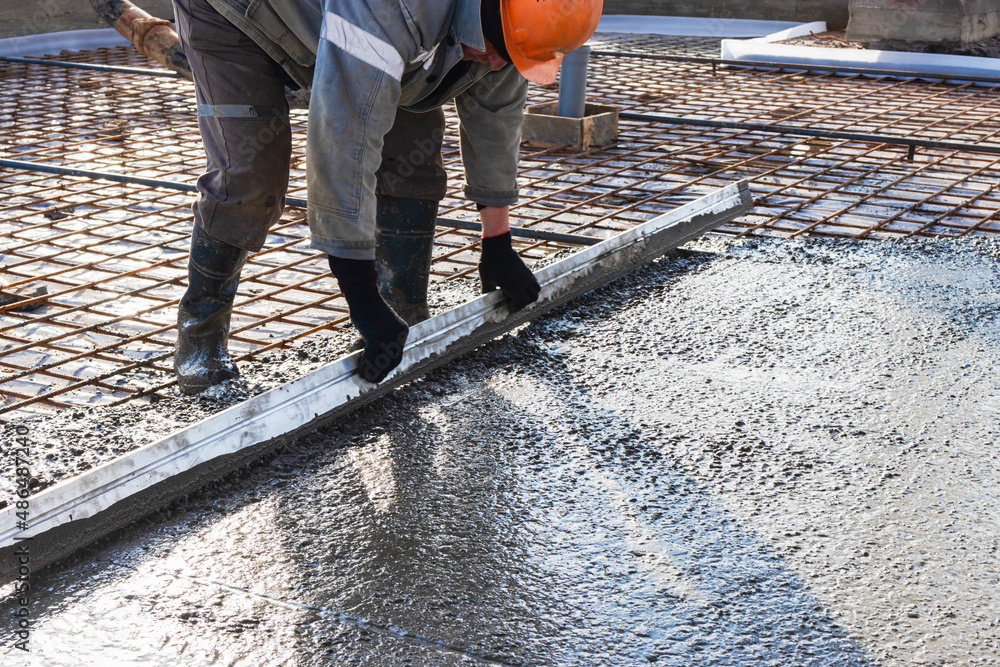Foto de Stock Construction worker leveling a poured concrete floor in ...