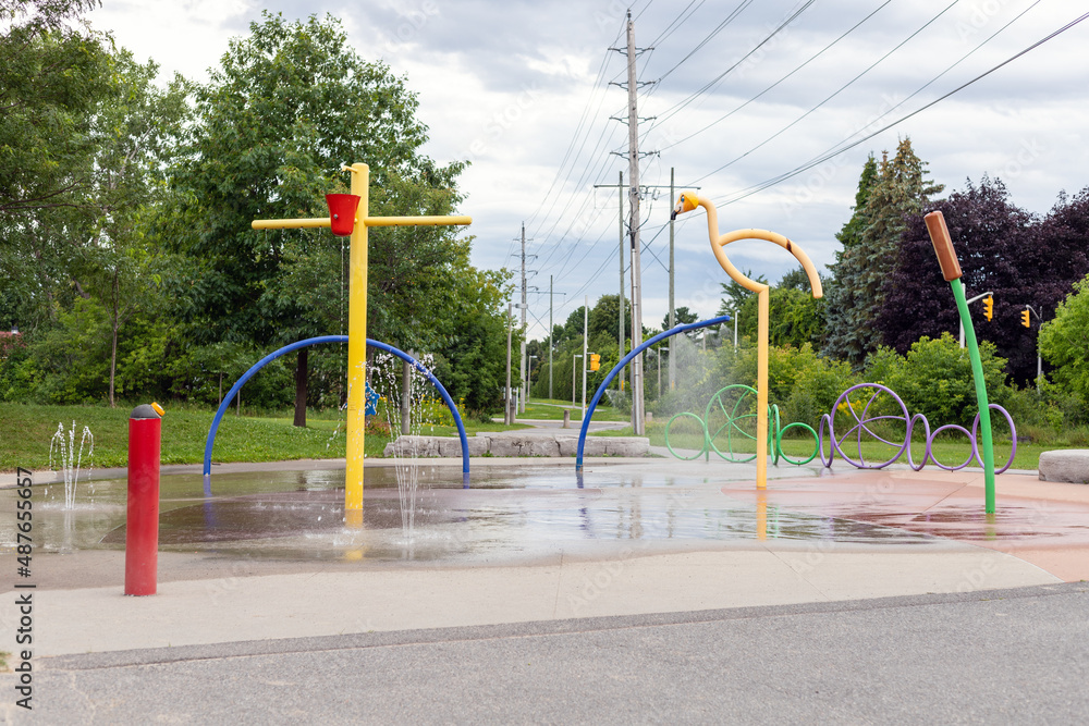 Splash pad playground in public park in summer without people. Fountains with splashing water ...