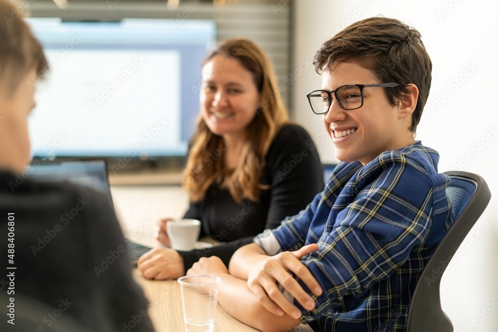 Smiling intern with the glasses talking to colleagues in the office ...