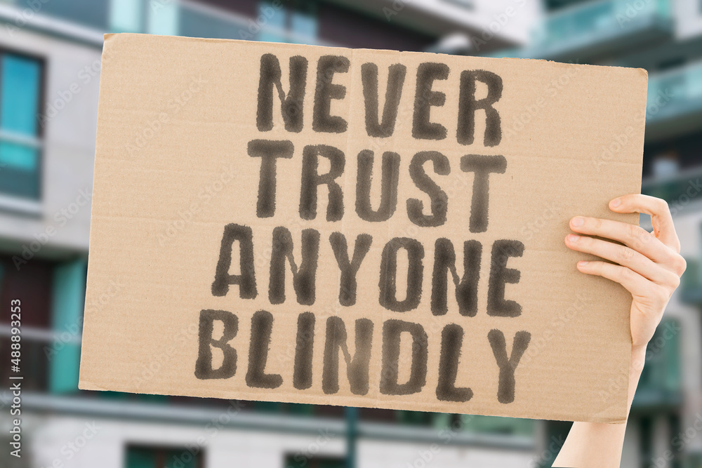 The phrase " Never trust anyone blindly " on a banner in men's hand ...