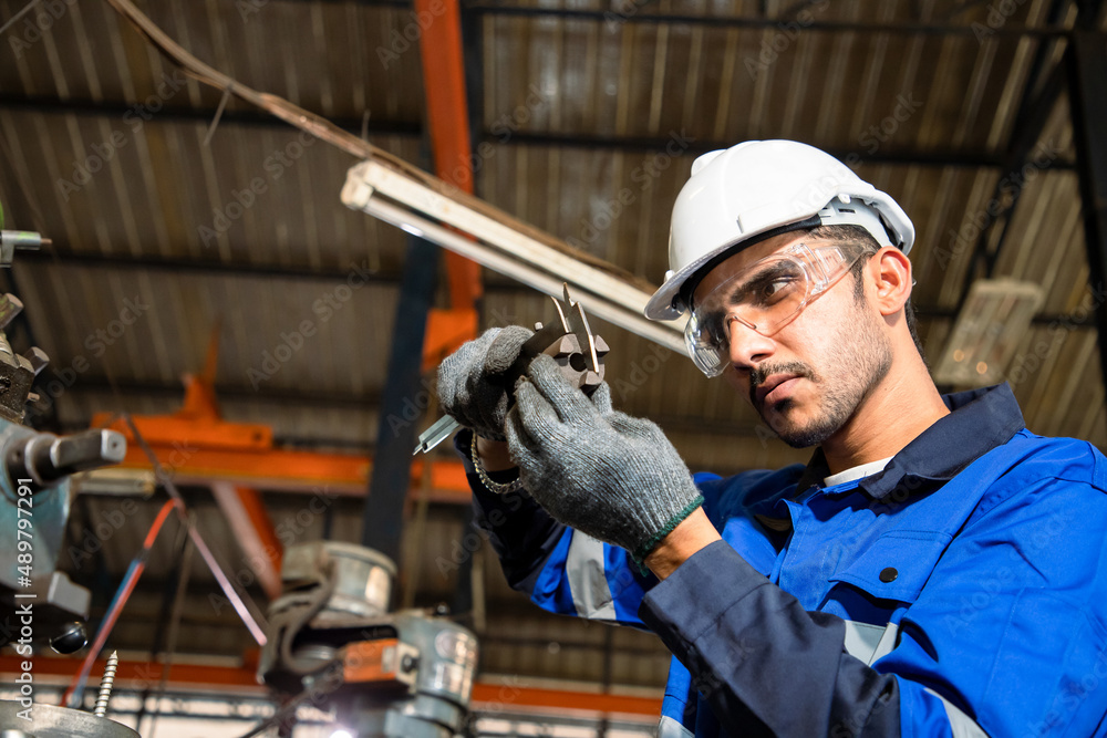 Handsome engineer worker wearing safety goggles measure the size of the ...