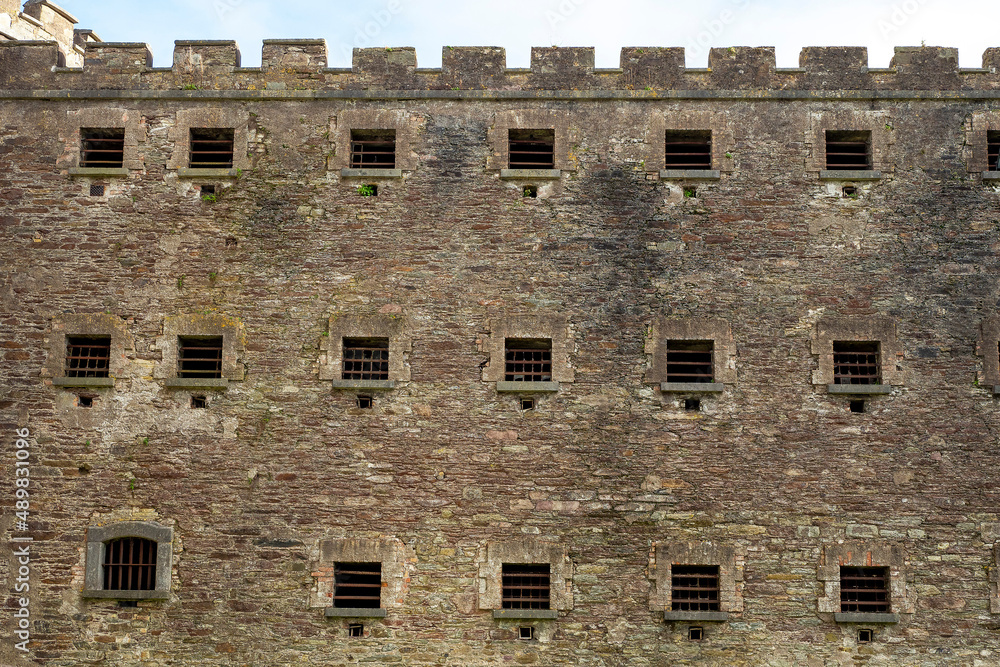 Old stone jail with very small windows with metal bars for male and female prisoners. Prison for ...