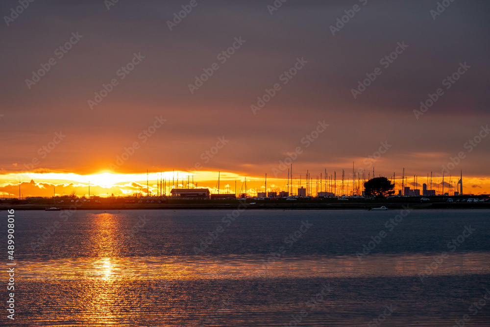 sun setting over the sea with Langstone bridge and The Spinnaker Tower ...