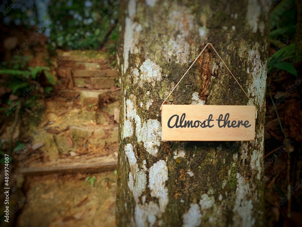 words of encouragement on a small signage - Almost there. Trees and ...