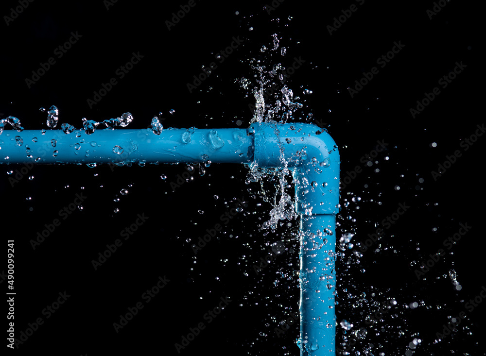 leaked and splash water from pvc plastic pipe over a black background ...