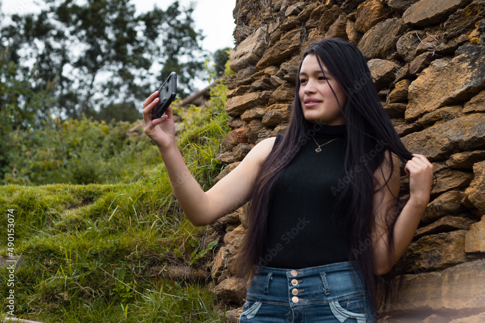 Una mujer joven con cabello largo y negro tomando selfies en el campo ...