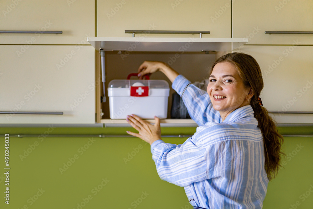 Domestic woman putting first aid kit with vitamins, drugs, antibiotics ...