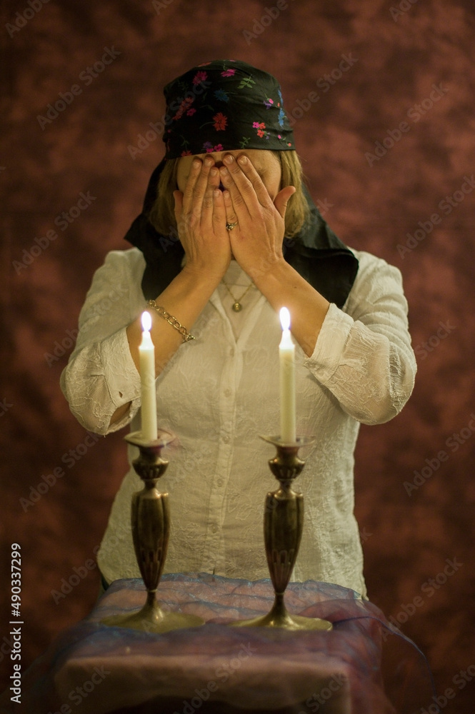 A traditional Orthodox Jewish woman with hair covered by a scarf covers ...