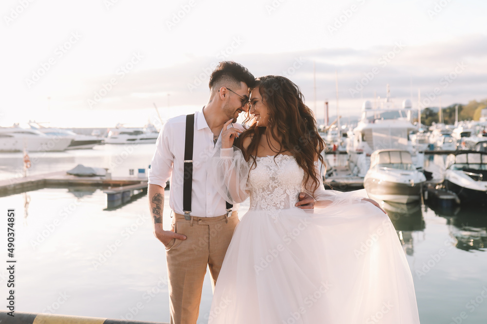 Happy lovers, the bride and groom in elegant wedding dresses go on a ...