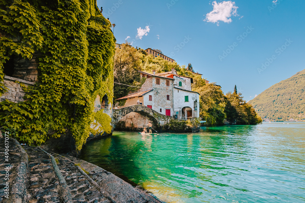 Village of Nesso with couple of people on surfboard under the medieval ...