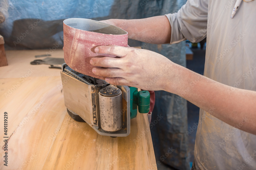 Removing a roll of worn sandpaper from a sanding machine or belt sander ...