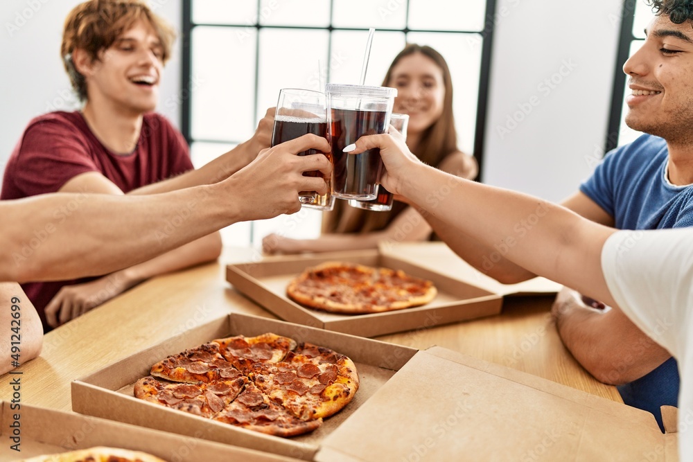Group of young friends smiling happy eating italian pizza and toasting ...