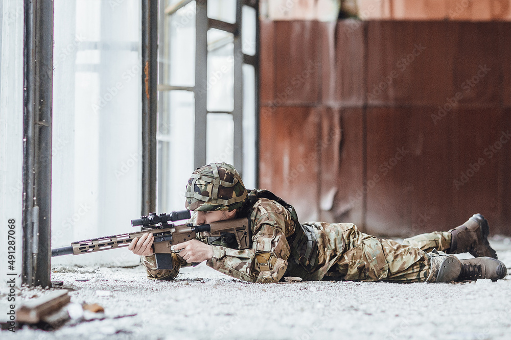 Military soldier in the uniform lay on the ground and holds in the ...