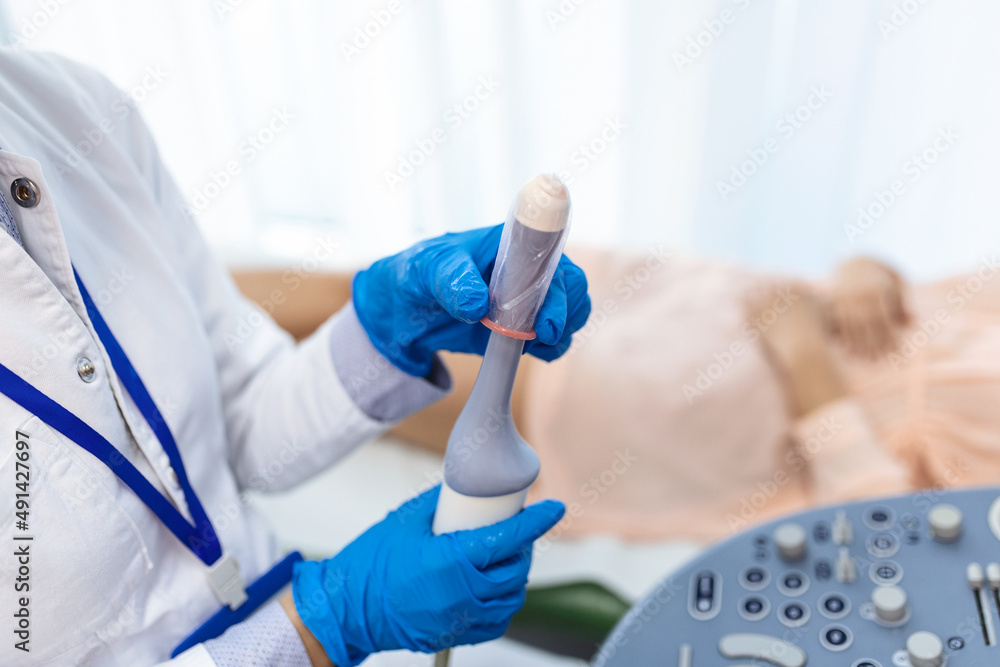 Gynecologist places ultrasound probe cover on a transvaginal ultrasound ...