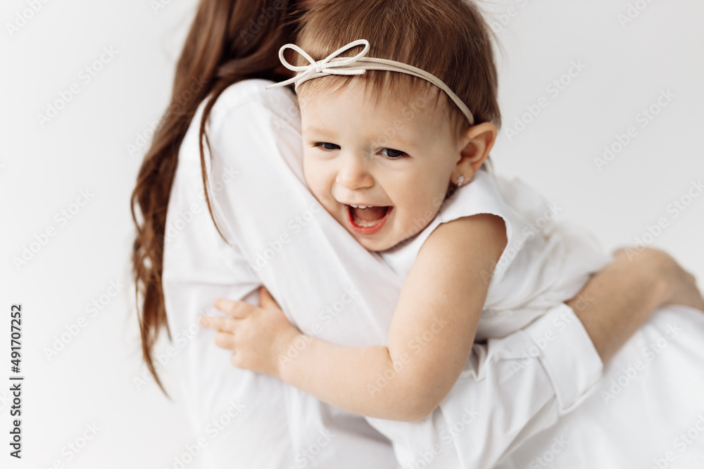 Close up of brunette young mother laying and holding baby girl. Attractive woman smiling and ...