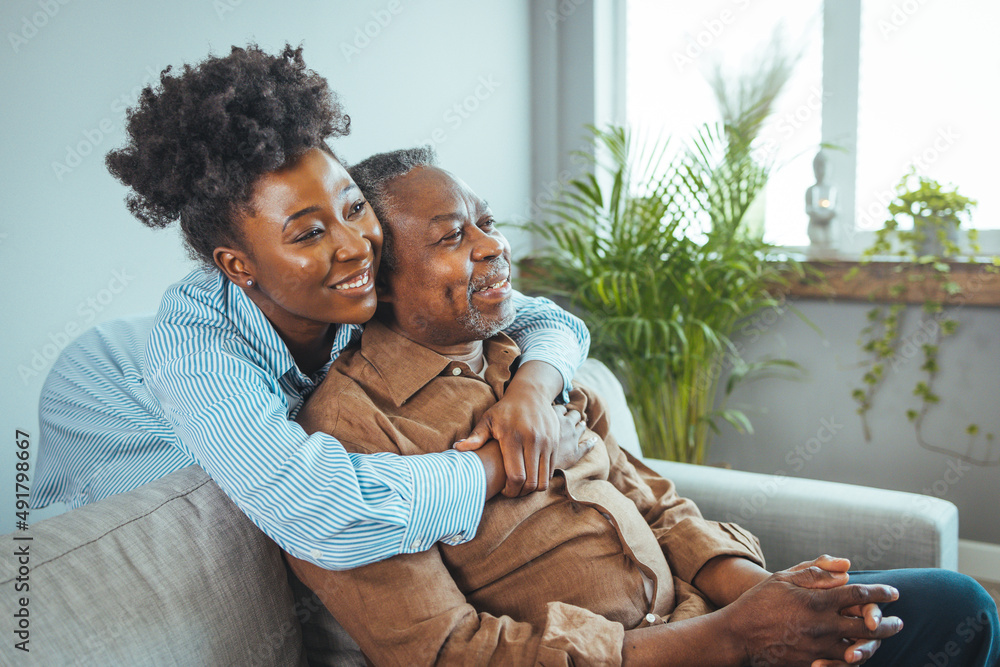 Smiling young woman sitting on sofa with happy older retired 70s father ...