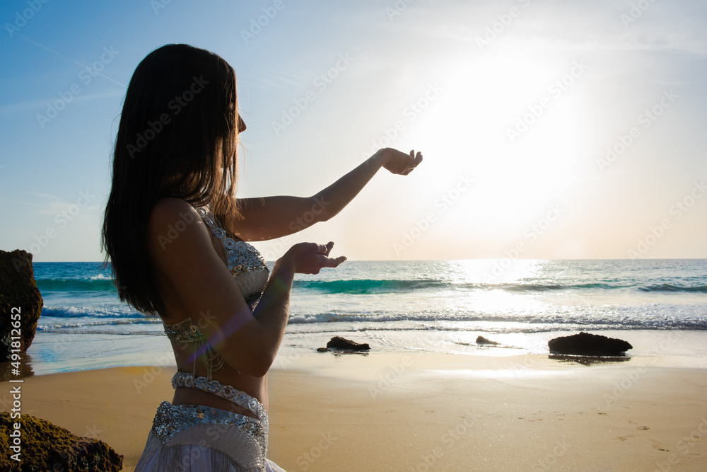 Happy and calm woman poses on the beach wearing the typical belly dance costume. Exotic beauty ...