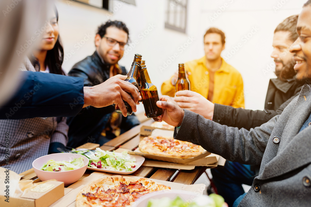 multiracial group of friends toasting with beer during the celebration ...