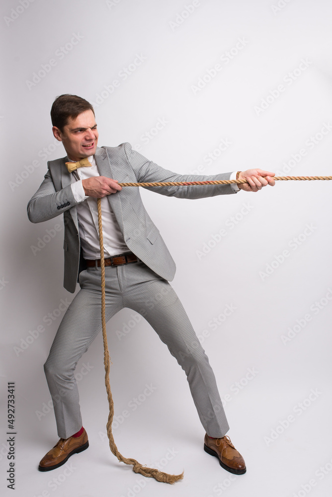 Strong man pulling rope. Photo of sporty man on grey background ...