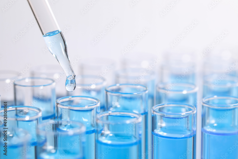 Dripping reagent into test tube on light background, closeup and space ...