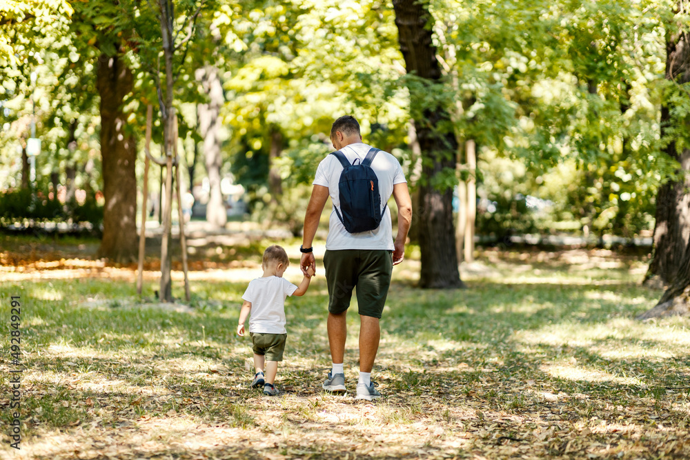 Father going for a walk with his little boy in nature on earth's day ...