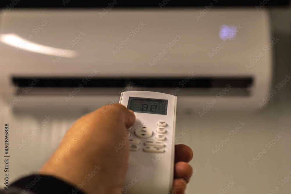 hand with the air conditioner control to set the desired temperature ...