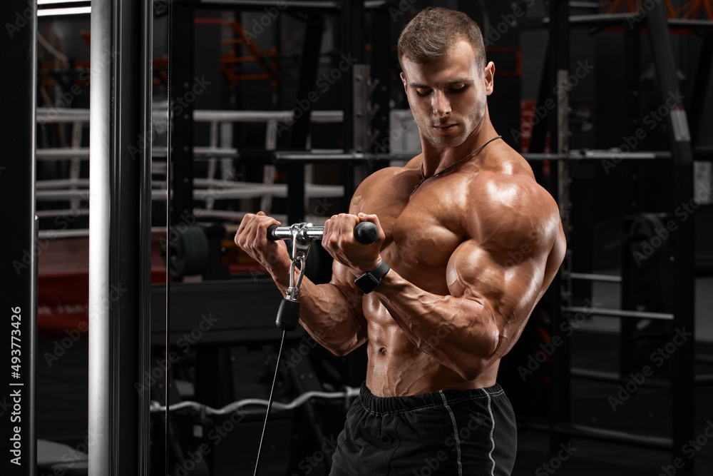 Stock-Foto „Muscular man in gym doing exercises for biceps, working out. Strong male naked torso ...